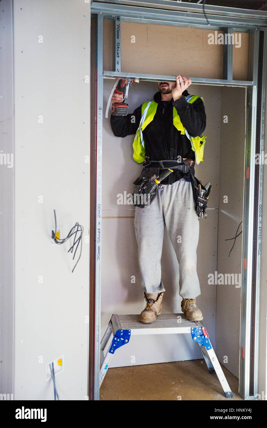 A carpenter in a small space fitting a shelf into a wall cupboard Stock ...