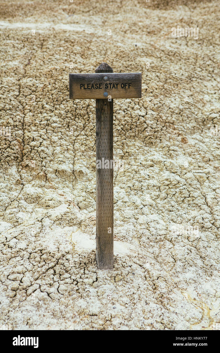 Cracked parched soil surface of the desert, and a Please Stay Off sign ...