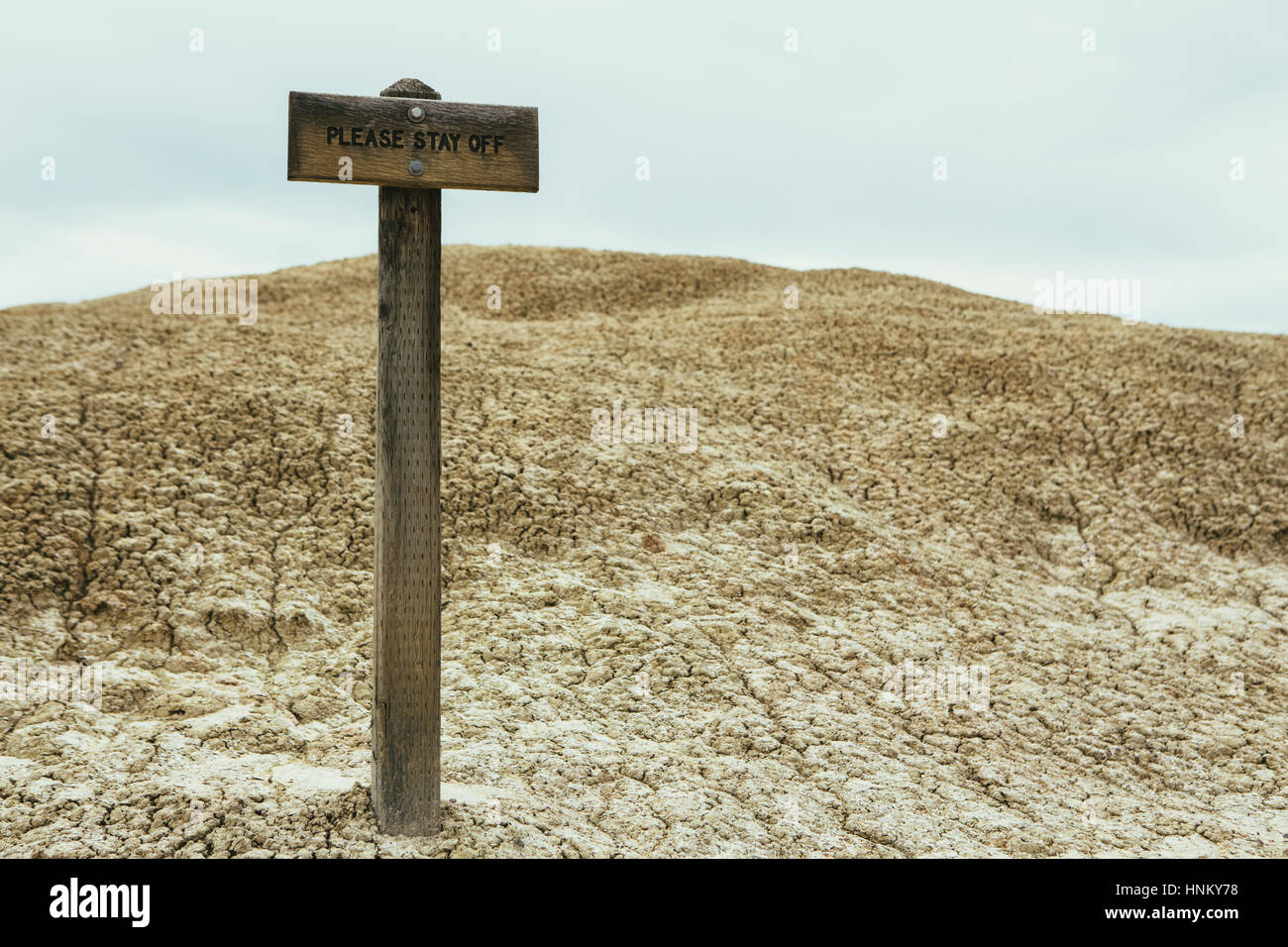 Cracked parched soil surface of the desert, and a Please Stay Off sign ...