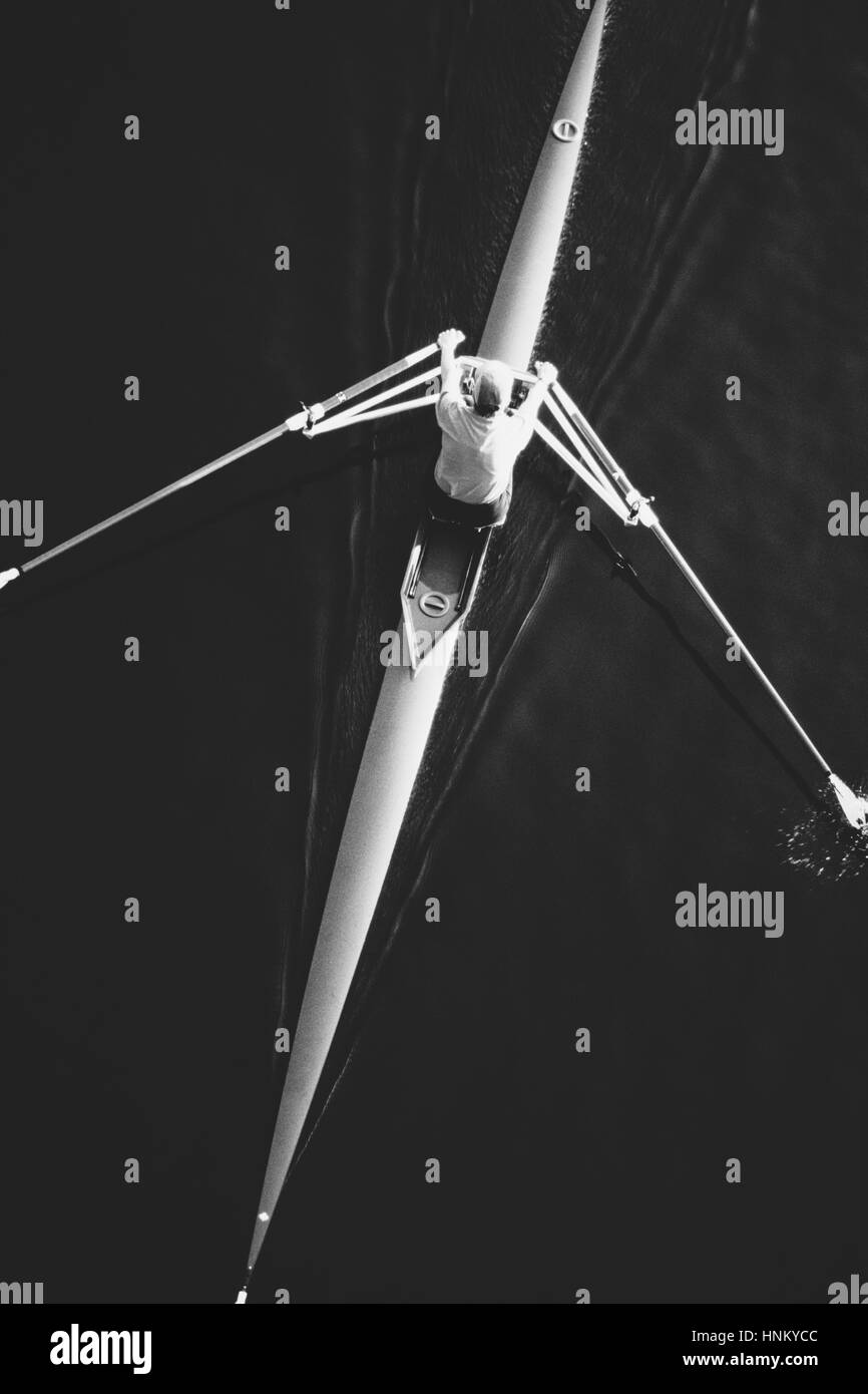A man sculling in a single scull rowing boat, on the water. Overhead ...