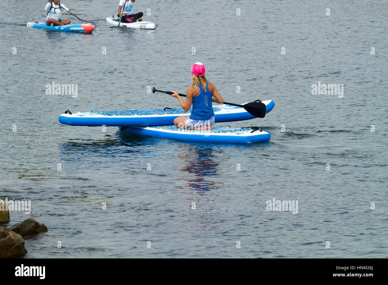 Young lady carrying an extra paddleboard while paddling Stock Photo - Alamy