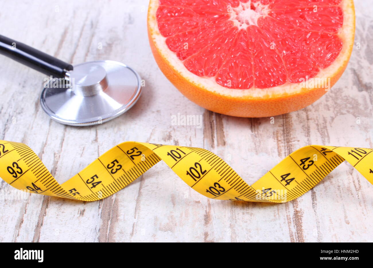 Fresh ripe grapefruit, tape measure and medical stethoscope on old ...