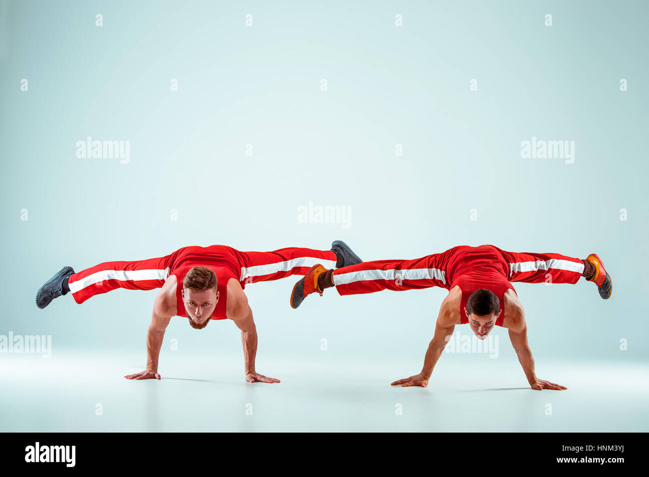 The two gymnastic acrobatic caucasian men posing in on gray studio ...