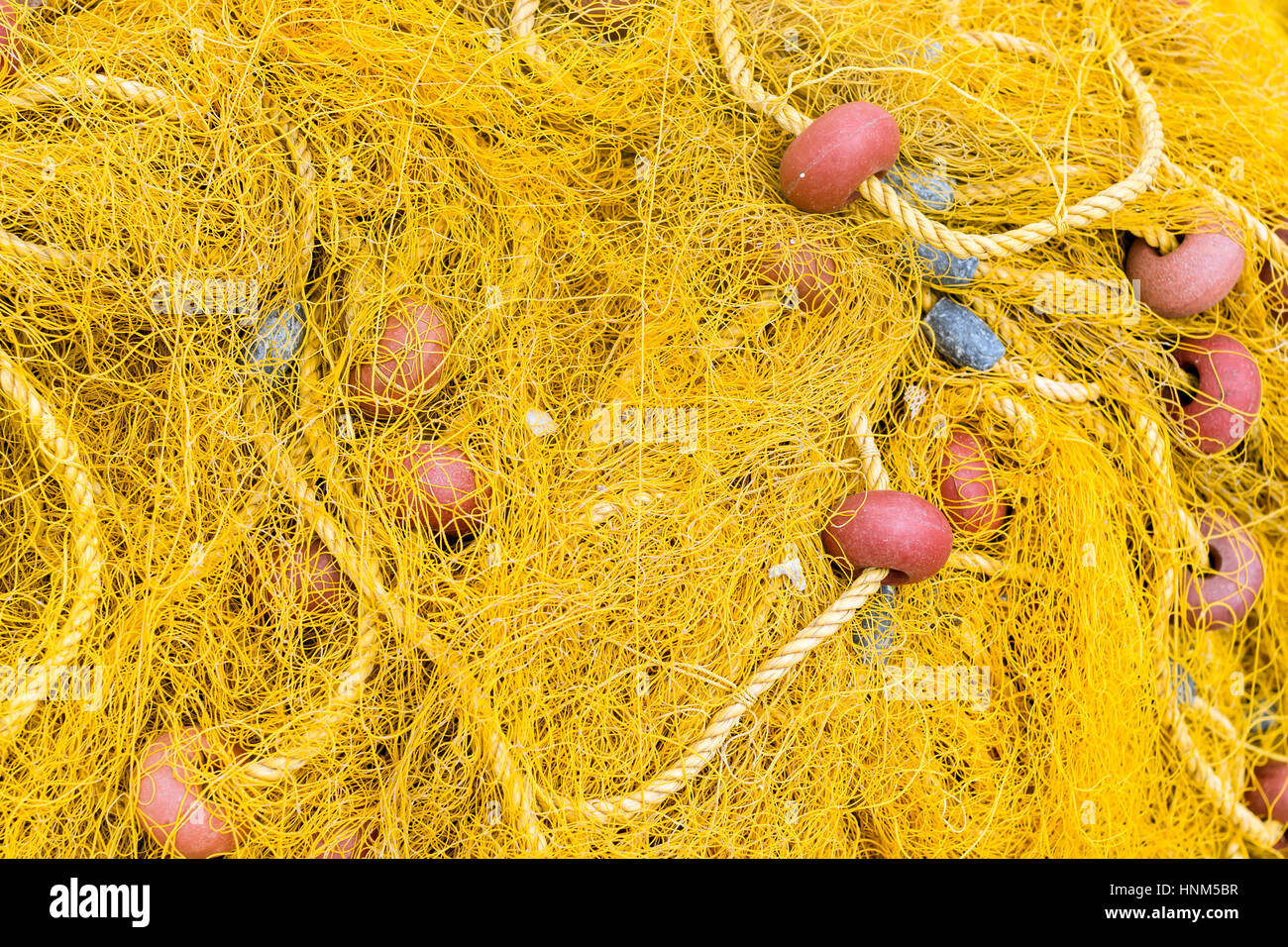 Empty yellow fishing net with floats lying on embankment of marine port ...
