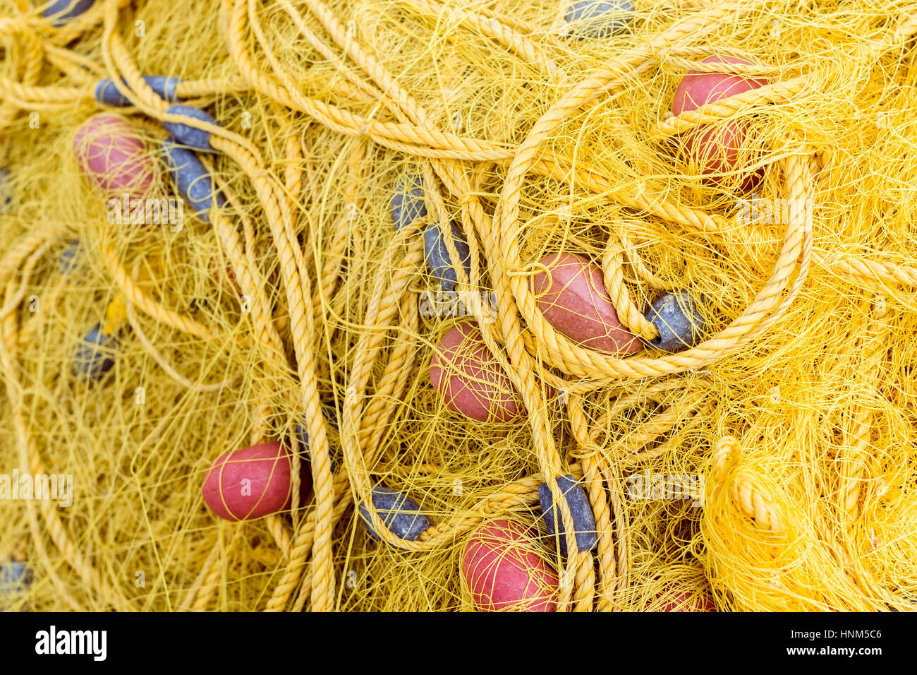 Empty yellow fishing net with floats lying on embankment of marine port ...