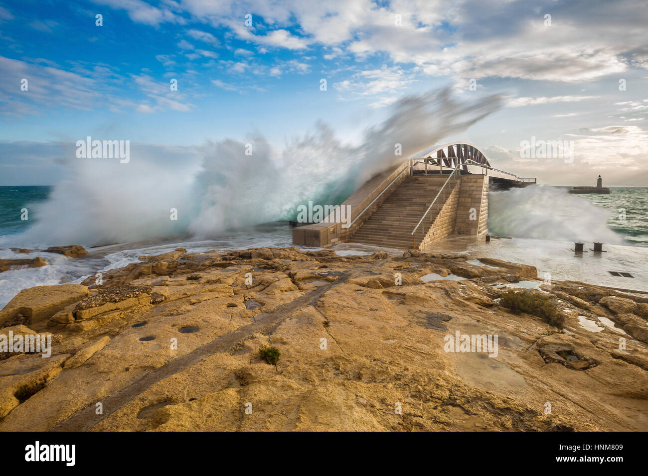Valletta, Malta - Strong waves over the Breakwater Bridge at sunrise ...