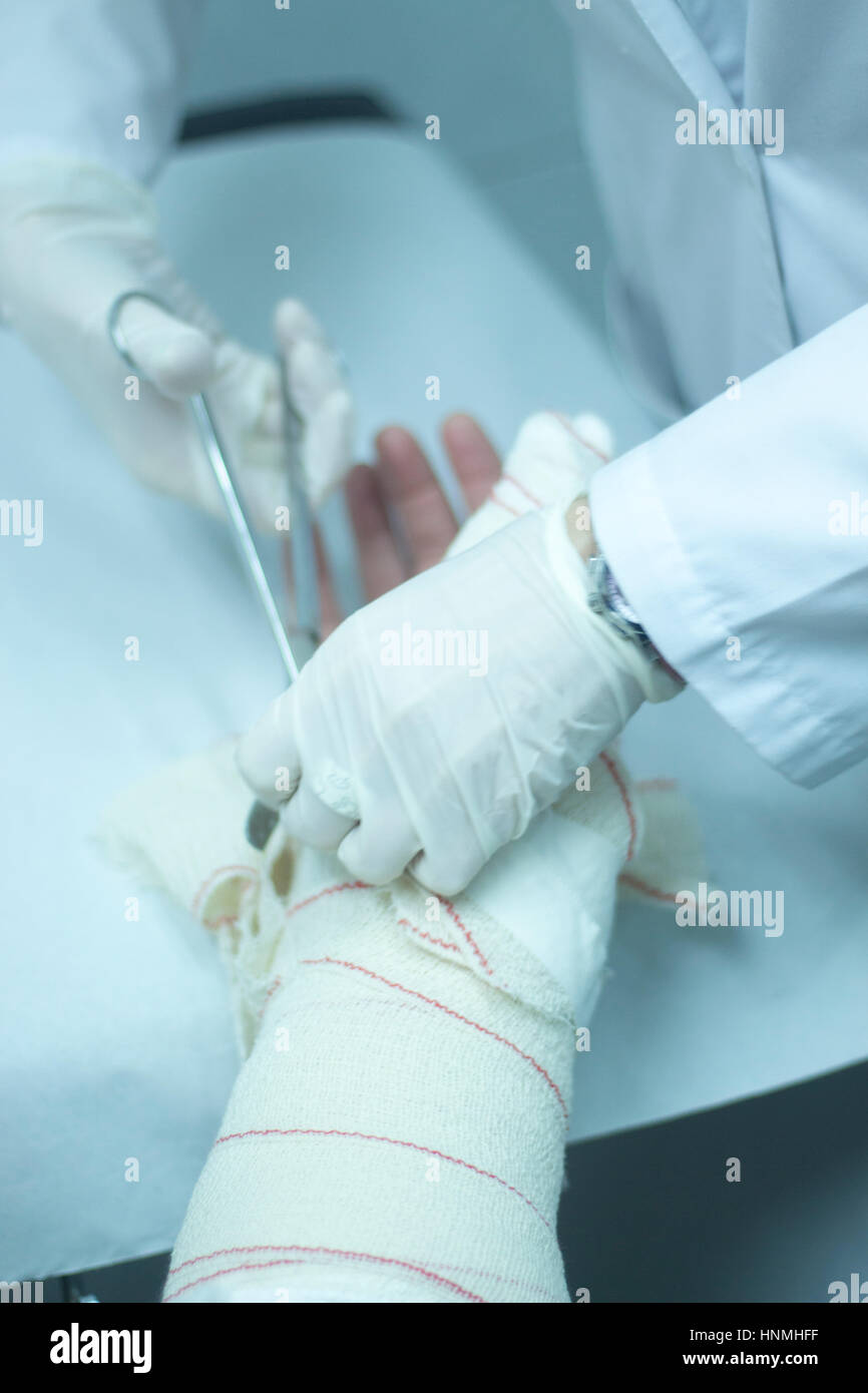 Doctor removing a plaster cast and bandages to patient forearm and ...