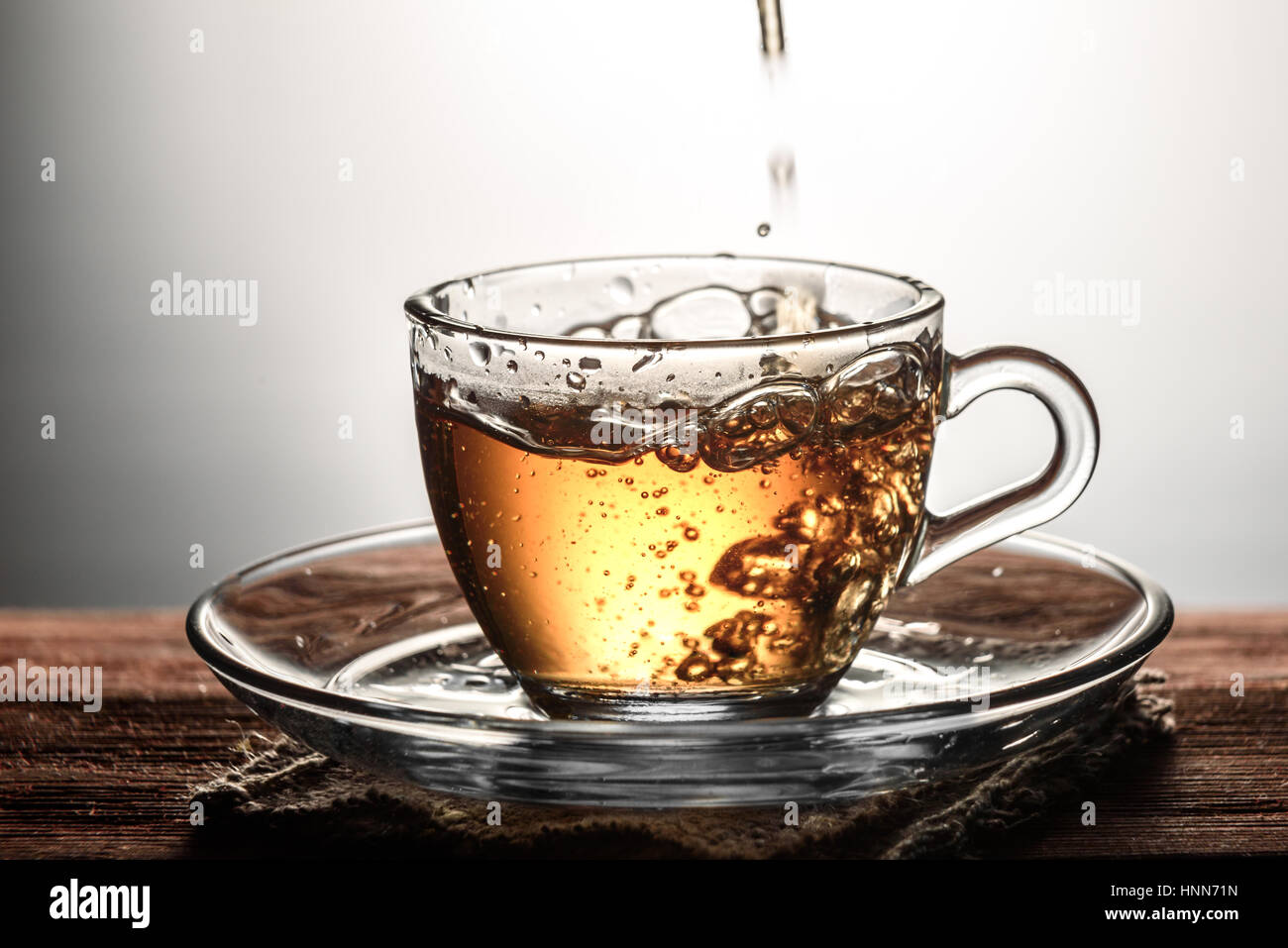 tea pouring into glass transparent Cup with bubbles on the wooden table ...