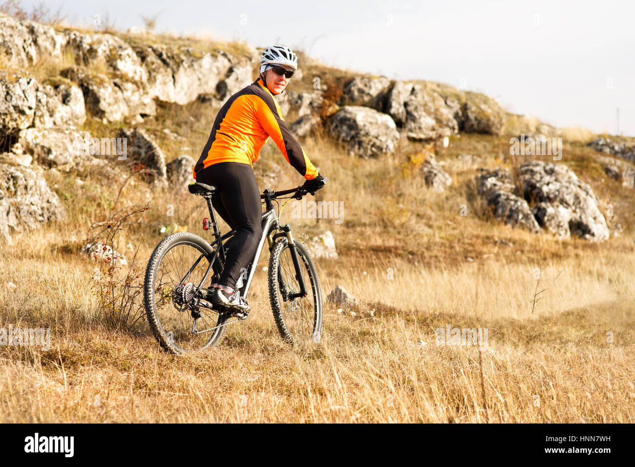 Cyclist in Orange Jacket Riding the Bike Rocky Hill. Extreme Sport ...