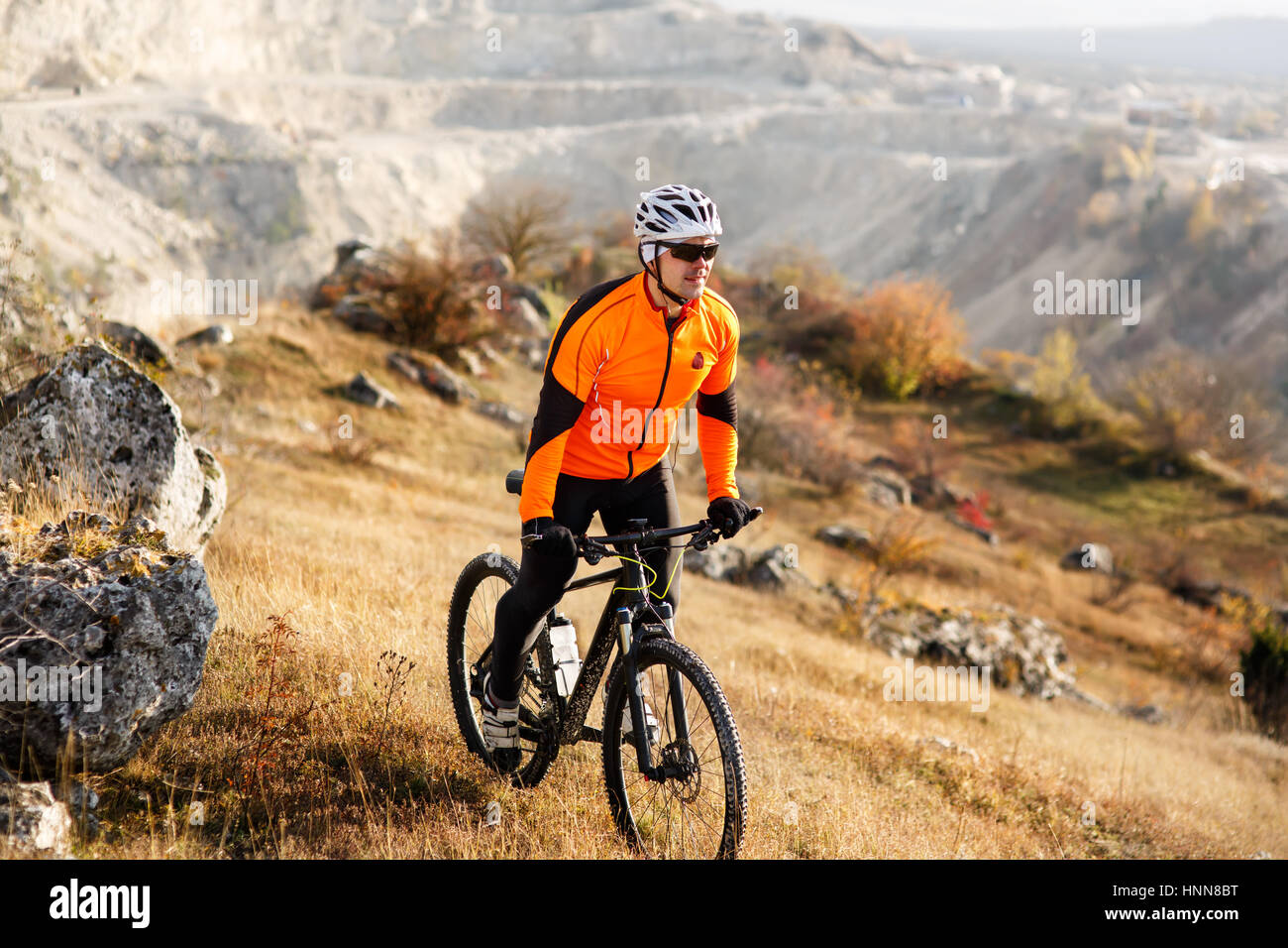 Cyclist in Orange Jacket Riding the Bike Rocky Hill. Extreme Sport ...
