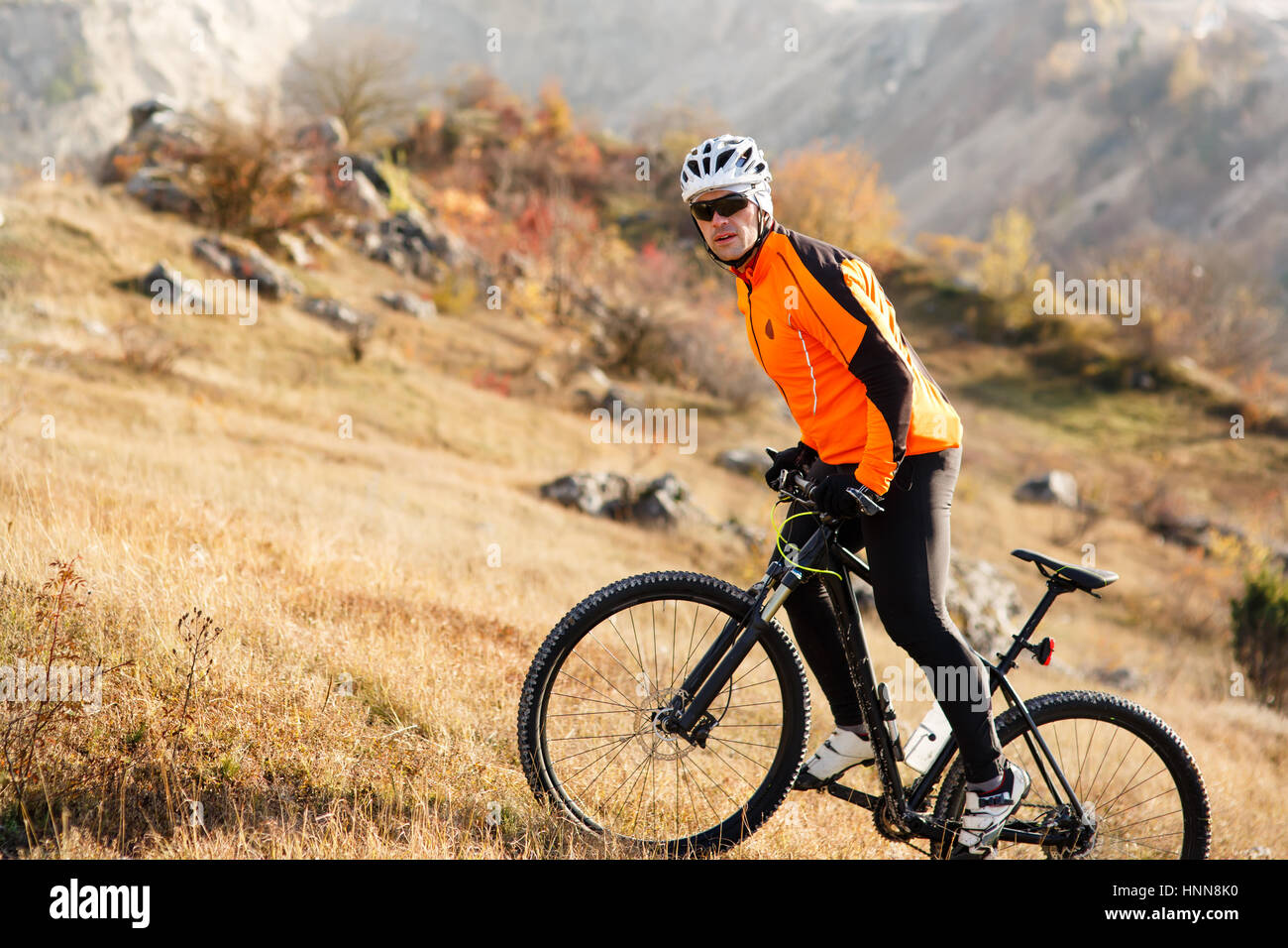 Cyclist in Orange Jacket Riding the Bike Rocky Hill. Extreme Sport ...
