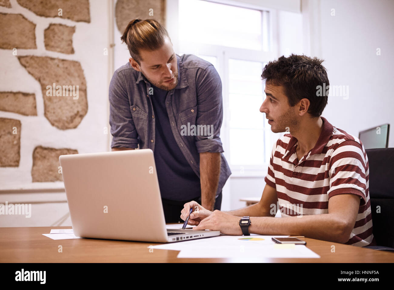 Two young business men planning a presentation looking thoughtfully at ...