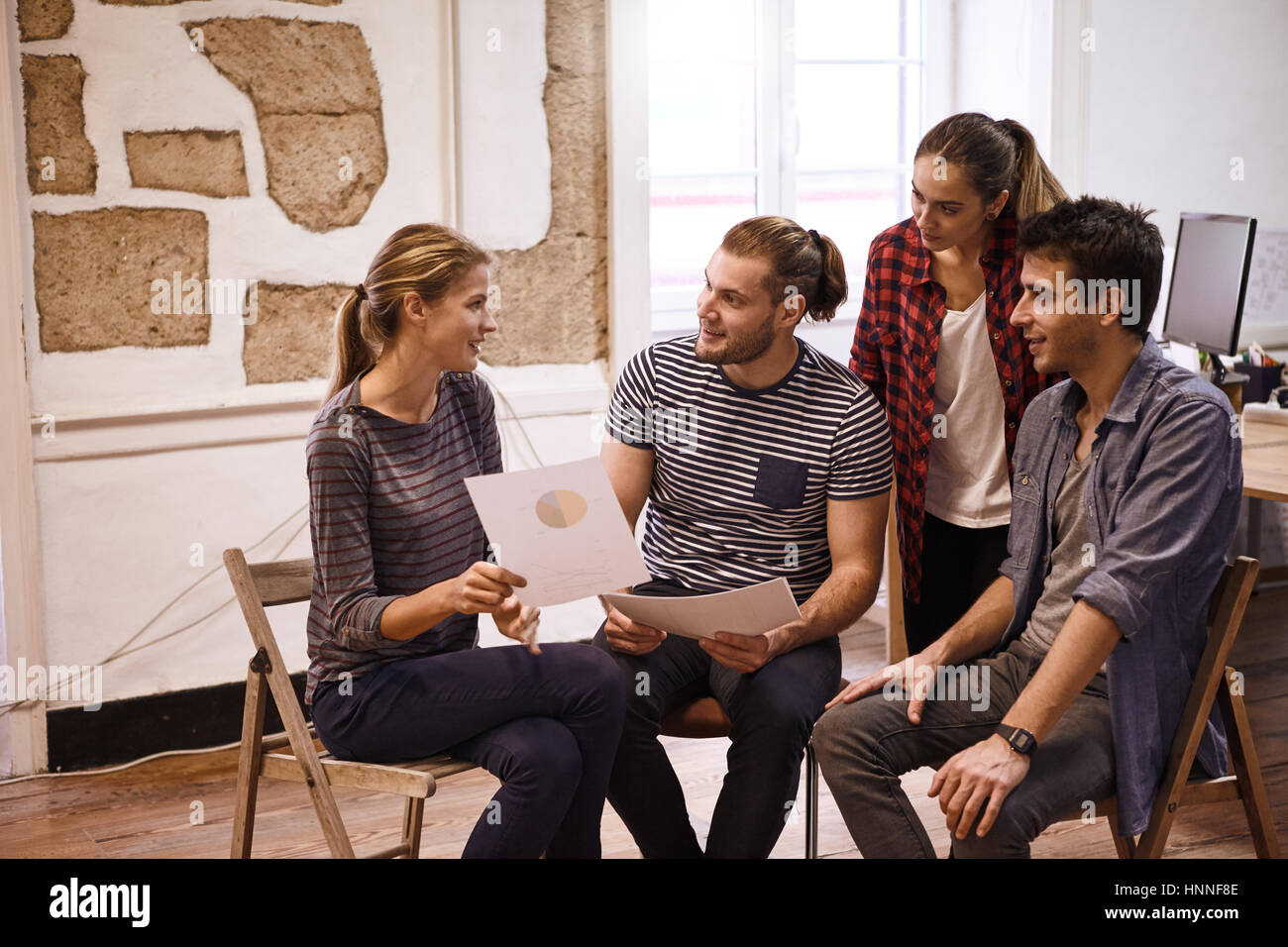 Inspirational young lady explaining a chart to the rest of the team who ...