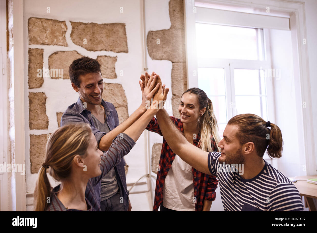 Four young people giving each other a high five with the girls looking ...