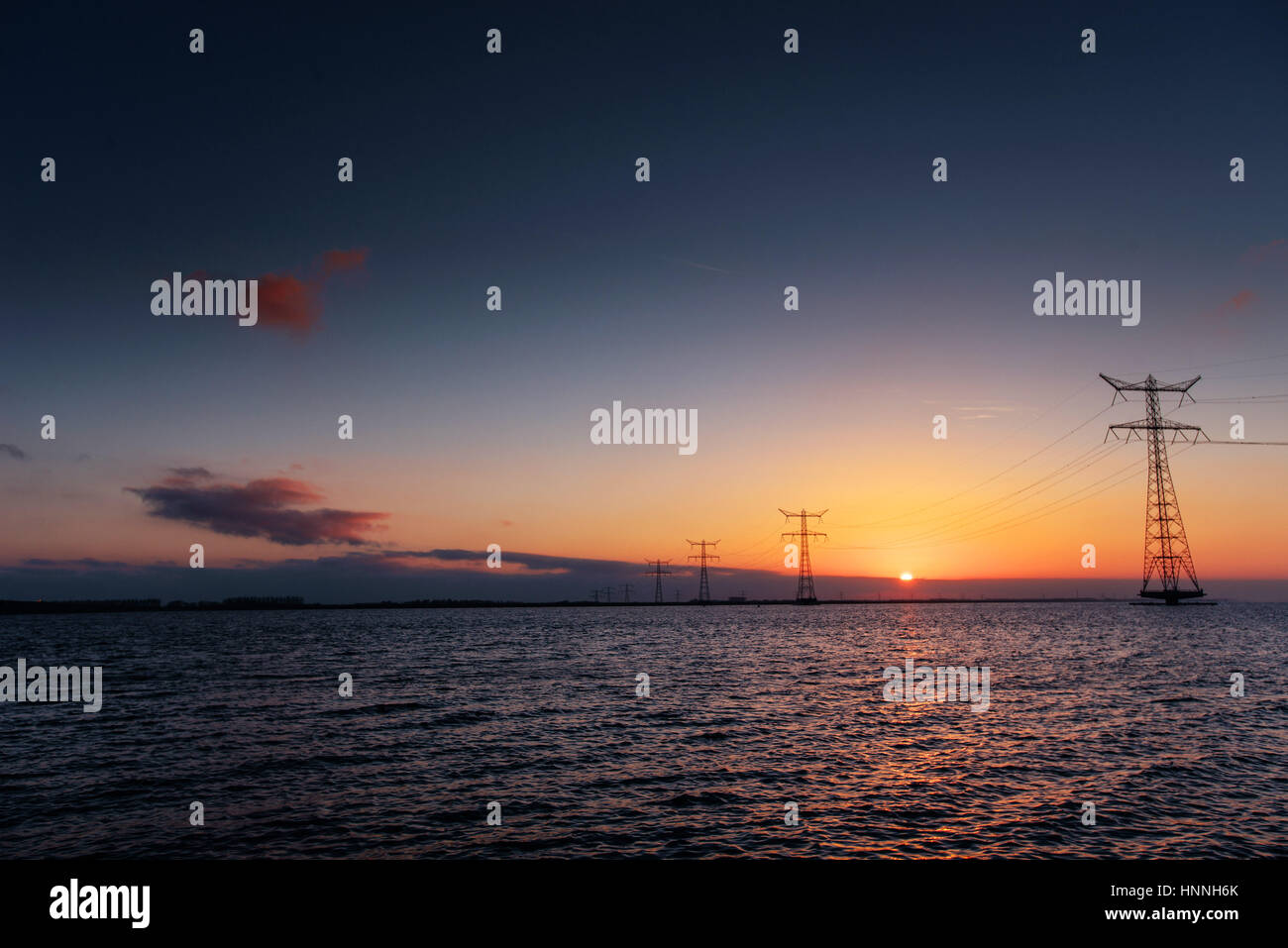 electric line above water during a fantastic sunset Stock Photo - Alamy