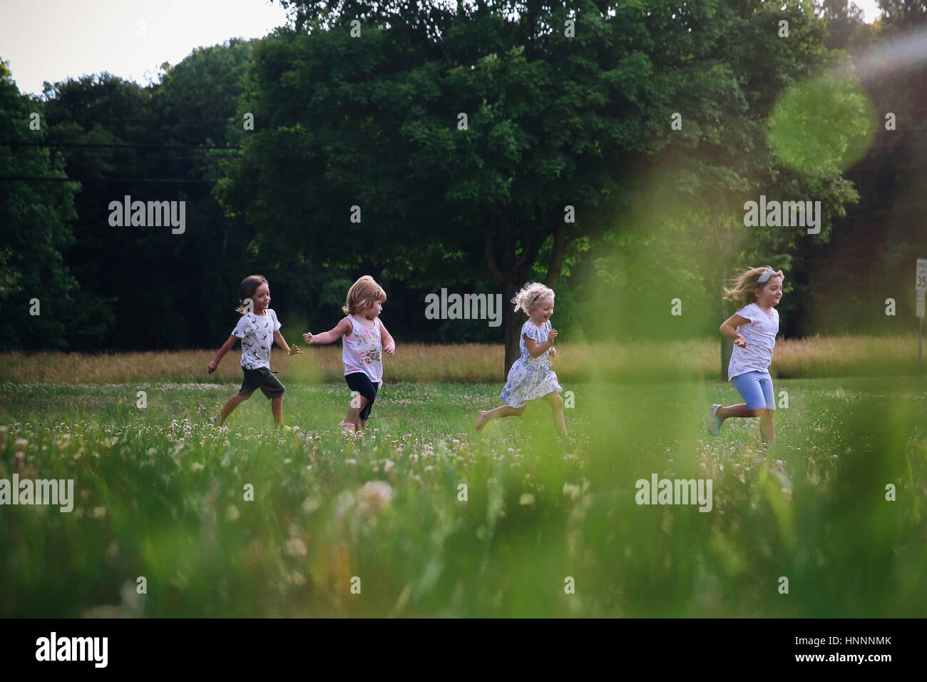 Friends running on grassy field at park Stock Photo - Alamy