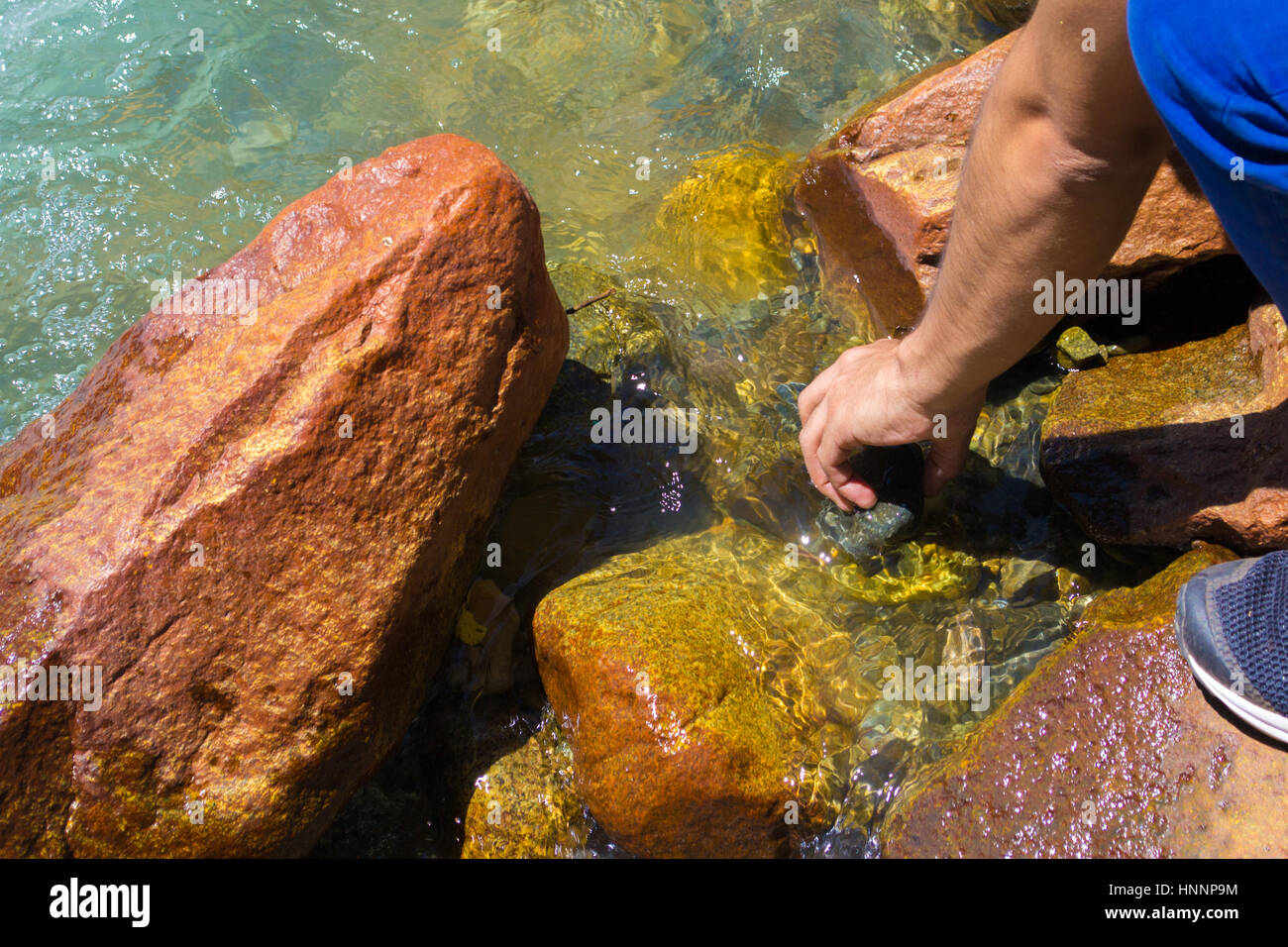A man grabbing a stone at the river Stock Photo - Alamy