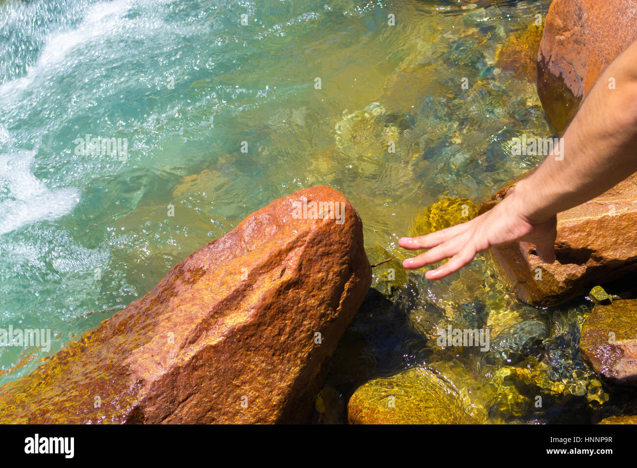 A man grabbing a stone at the river Stock Photo - Alamy