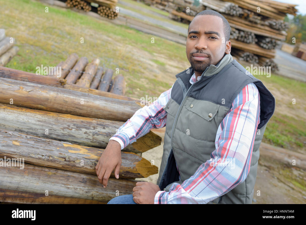 Portrait of man next to stack of wood Stock Photo - Alamy