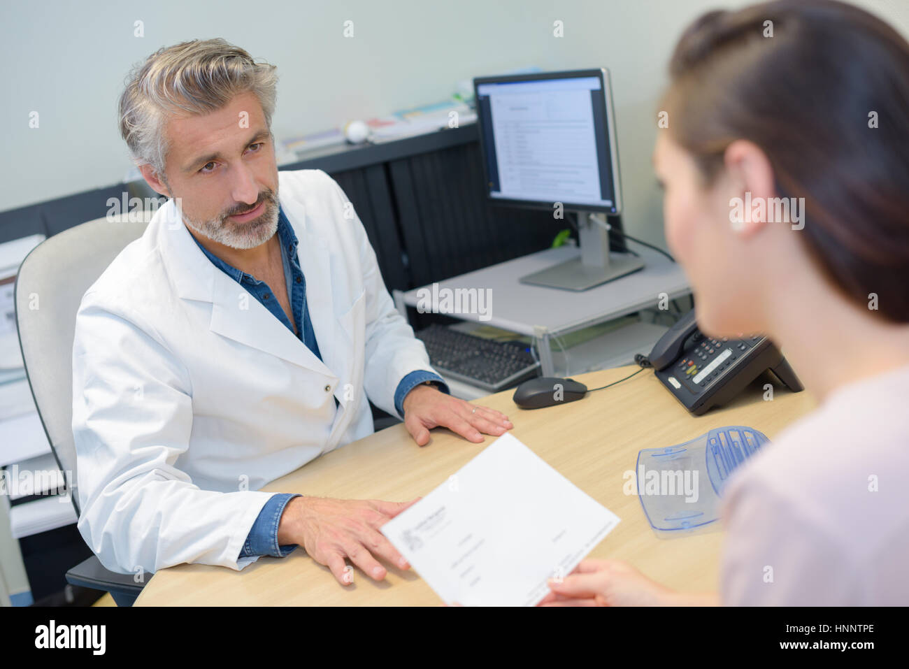 Doctor passing prescription to female patient Stock Photo - Alamy