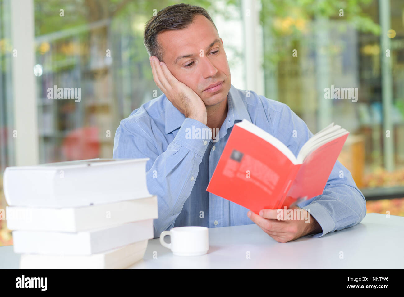 Man reading book, looking bored Stock Photo - Alamy