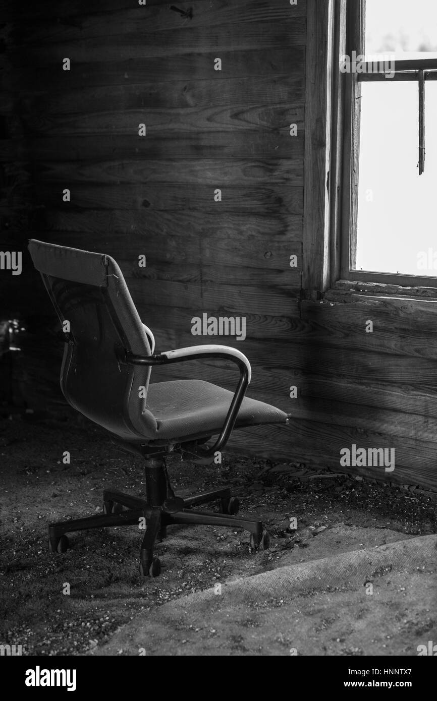 A lonely chair sits facing a window in an abandoned house in North ...