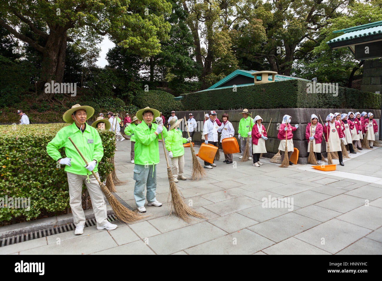 TOKYO, JAPAN - CIRCA APR, 2013: Cleaning workers with brooms in red and ...