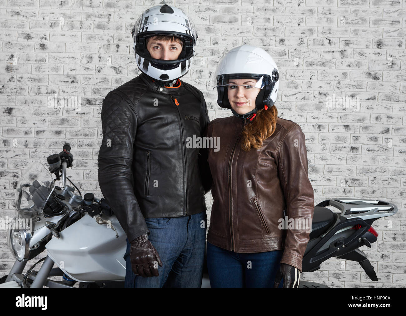 Young loving couple in a motorcycle outfit and helmets standing ...