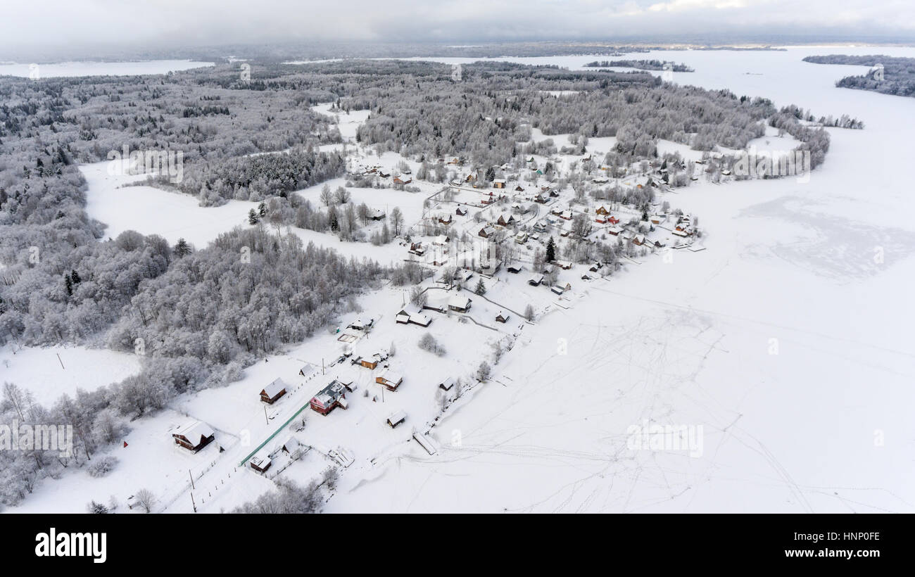Panorama of winter lake shore with remote village in evergreen forests ...