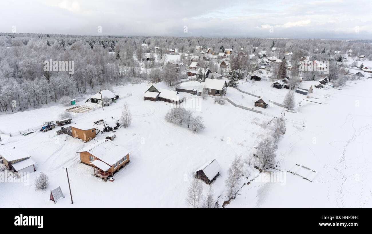 Rural timber houses and barns are on winter lake shore. Russian remote ...