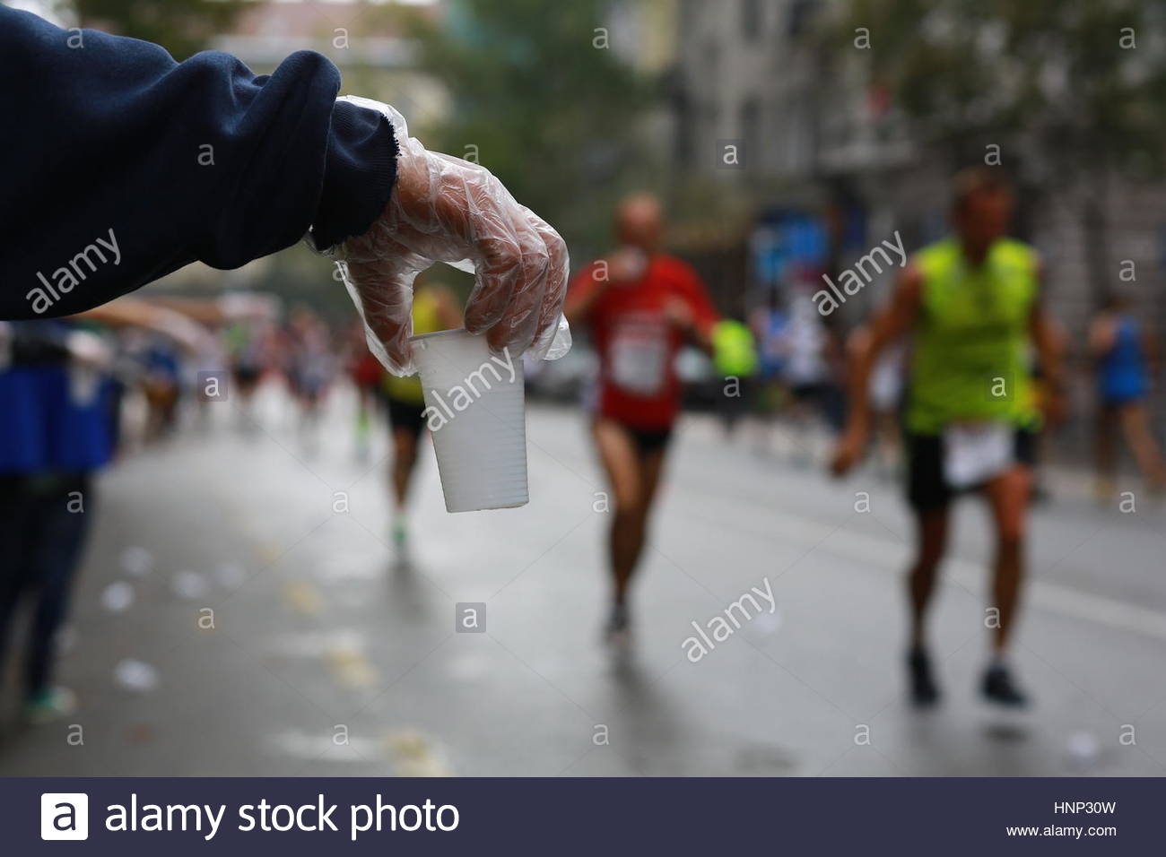 A volunteer offers a cup of water to runners at a marathon in the city ...