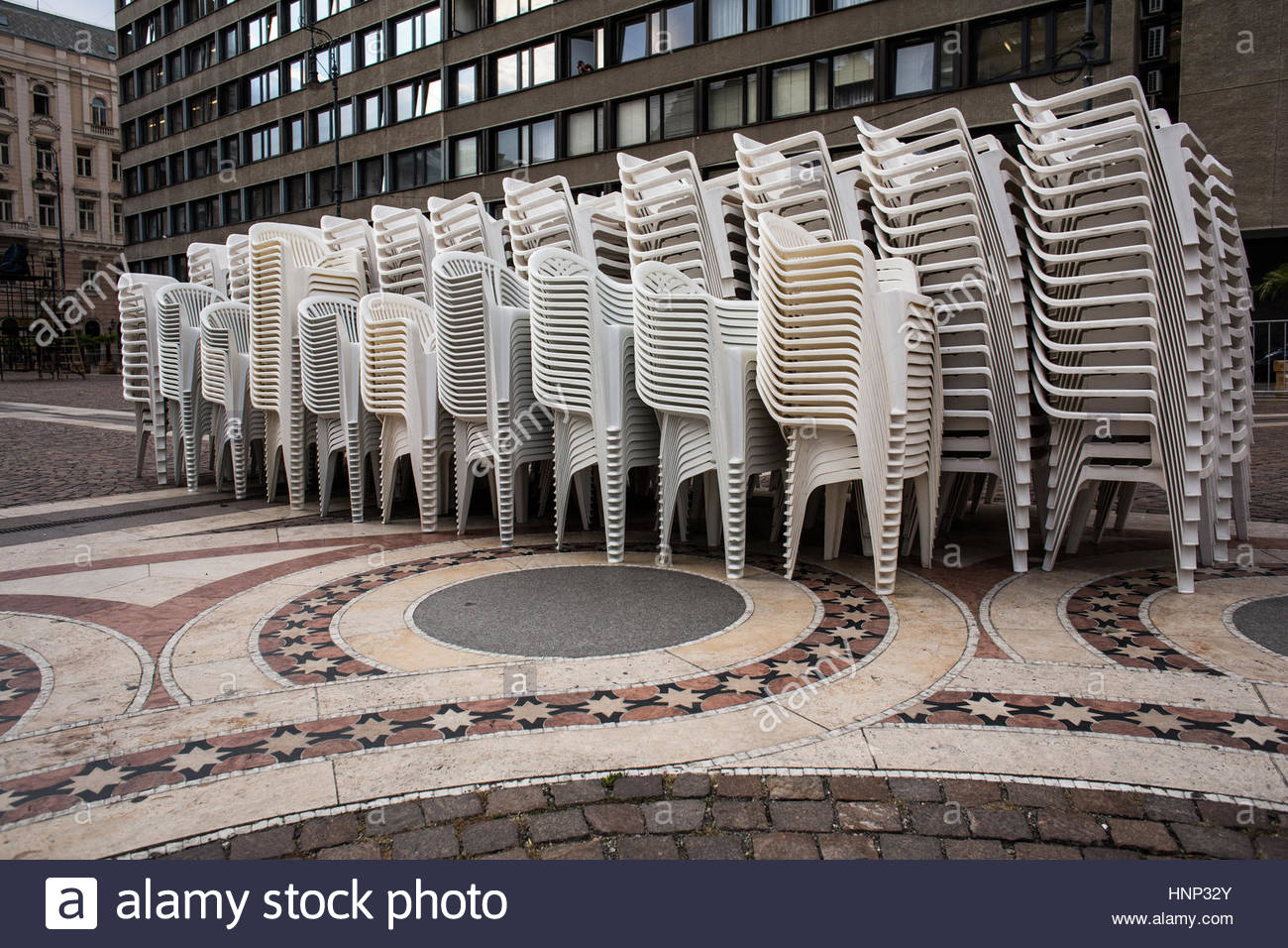 Chairs stand stacked and ready for use at an open air event in a city ...