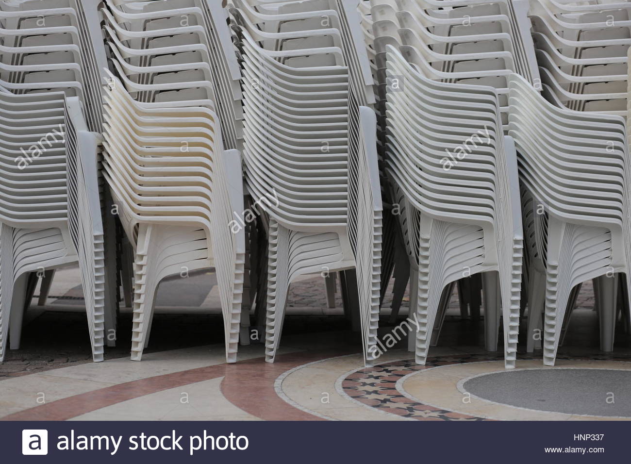 Chairs stand stacked and ready for use at an open air event in a city ...