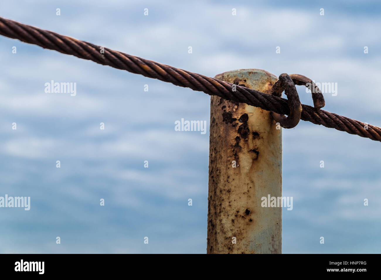 Column with sling railing around a rusty ship on cloudy blue sky ...