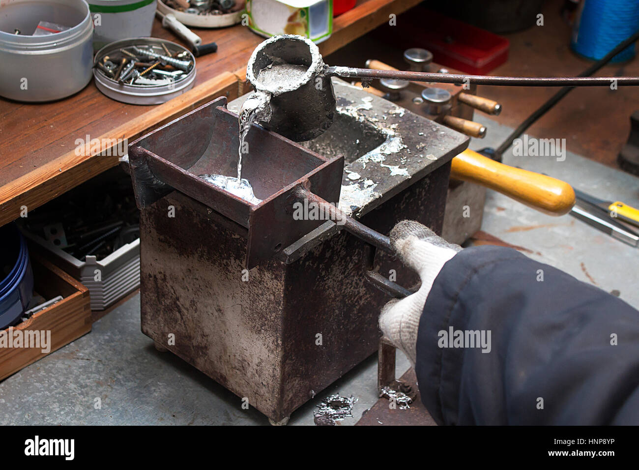 Pouring molten lead alloy into a mold. Workshop. Manufactory, manual ...