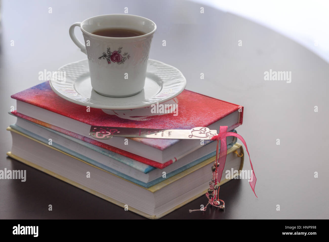 Teacup on books with pink bookmark Stock Photo - Alamy