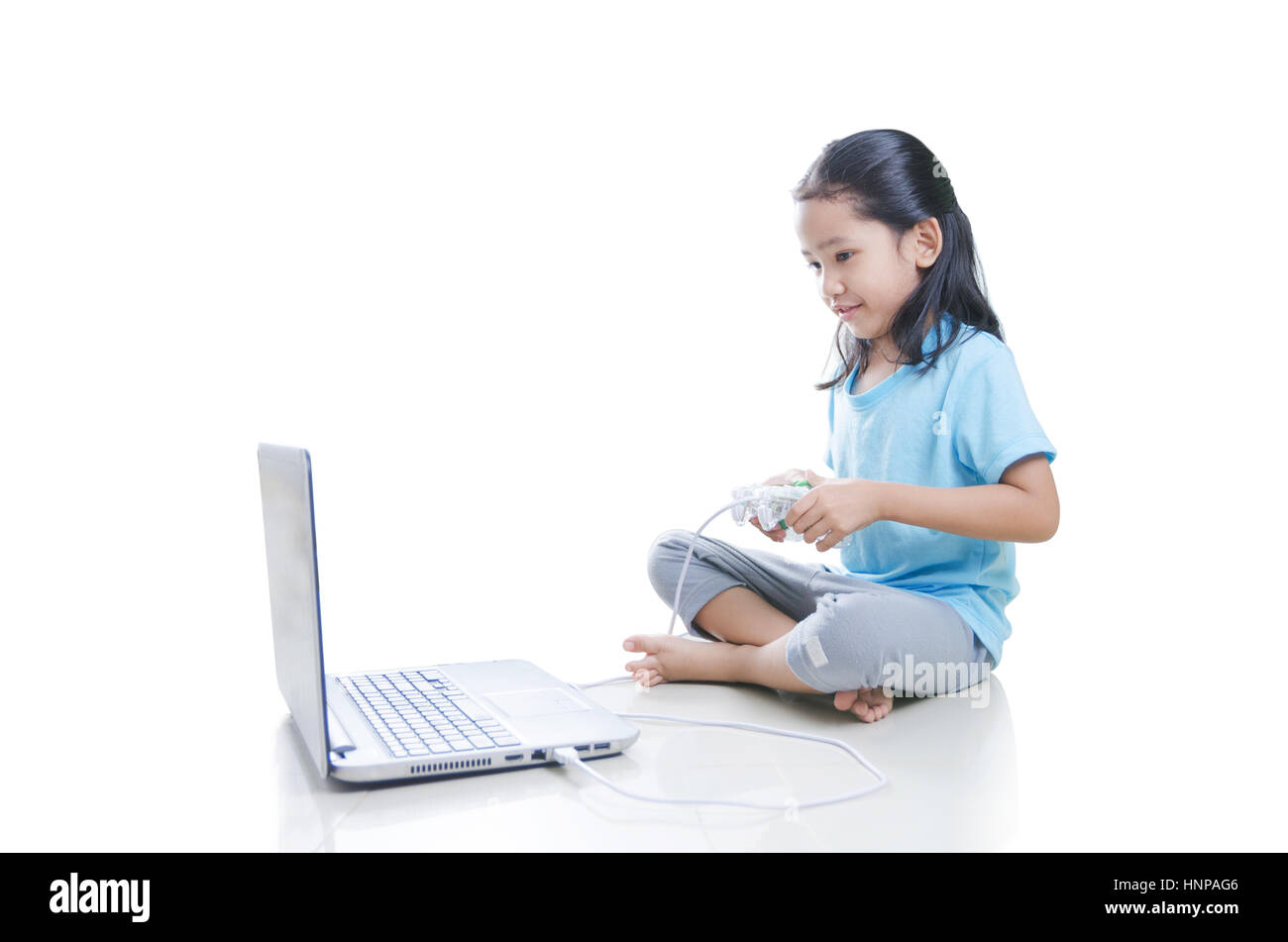 Asian little girl playing games with laptop computer and joystick ...