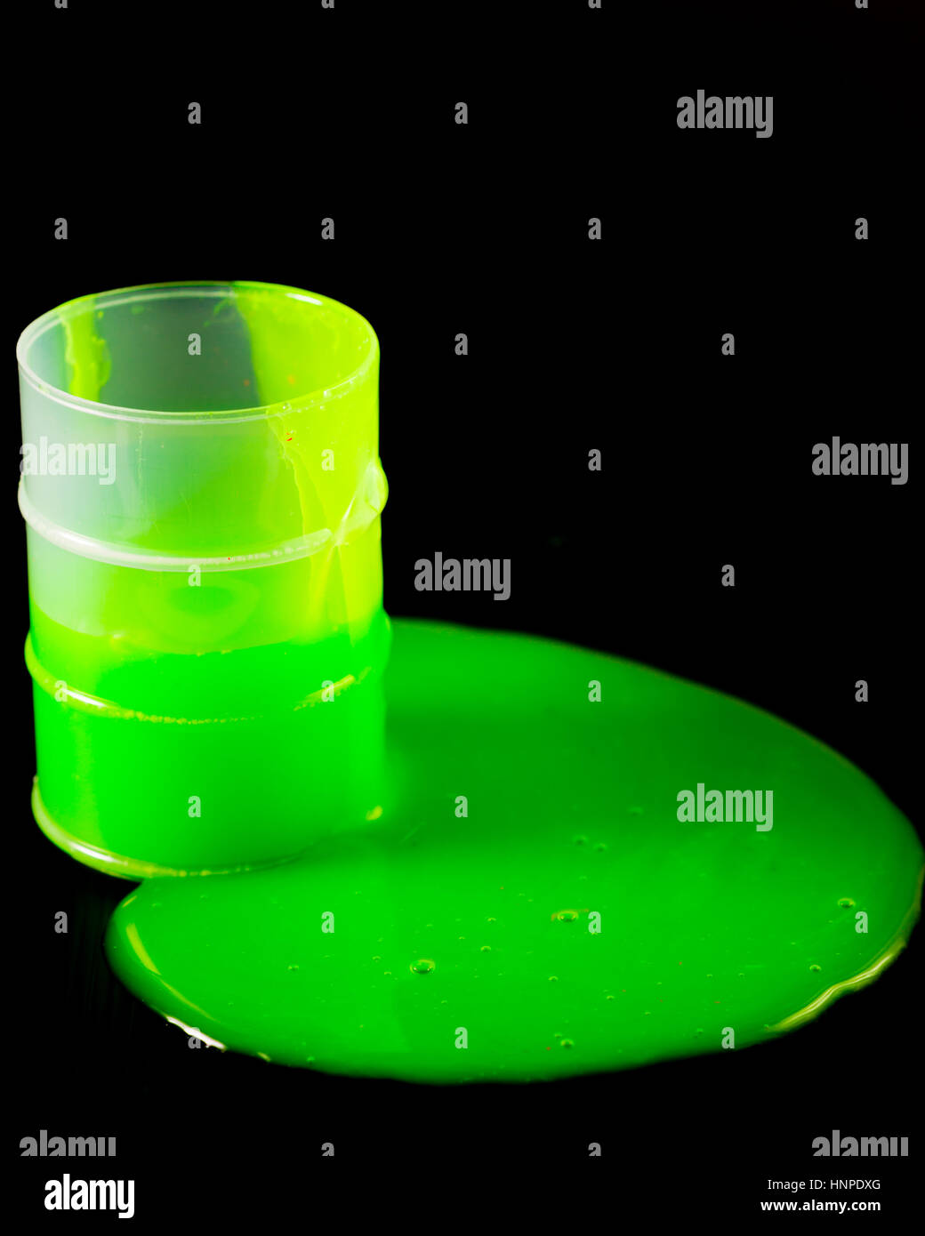 Green slime spllling out of barrel on black background Stock Photo - Alamy