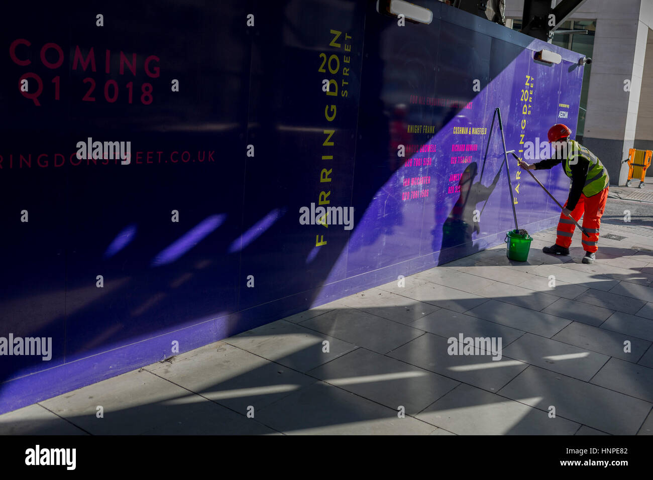 A contractor cleans construction hoarding on Farringdon Street, on 13th ...