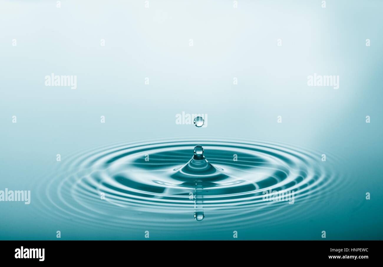 Water drop falling and drips on water mirror. Water drop splash and ...