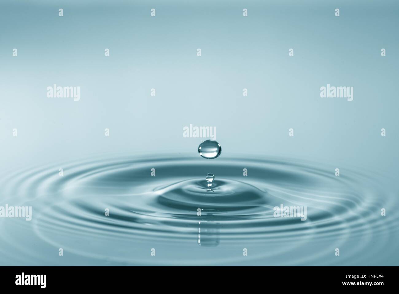 Water drop falling and drips on water mirror. Drops splash and make ...