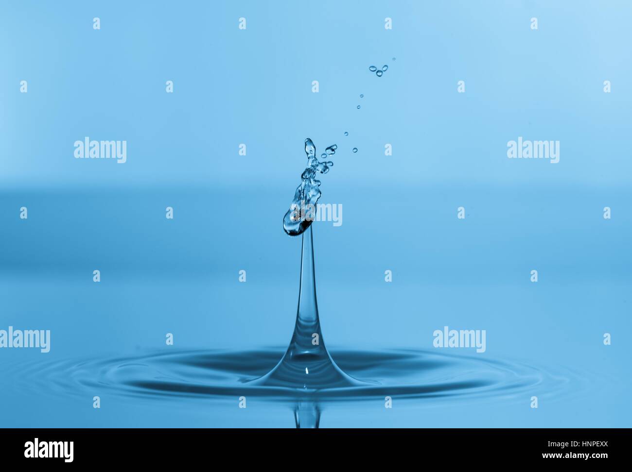 Water drop falling and drips on water mirror. Water drop splash and ...
