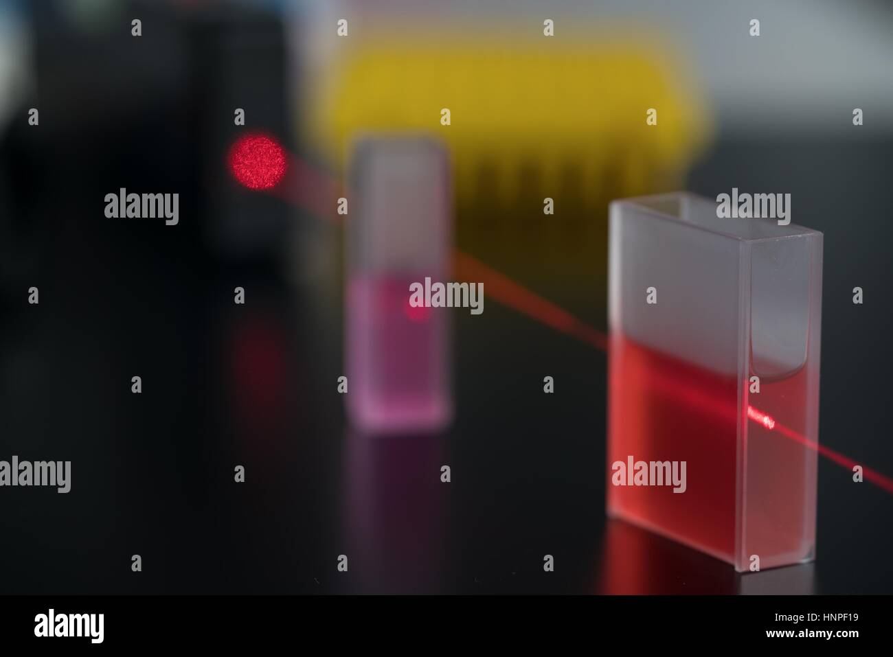 Quartz cuvette for laser chromatography with red liquid. Physical ...