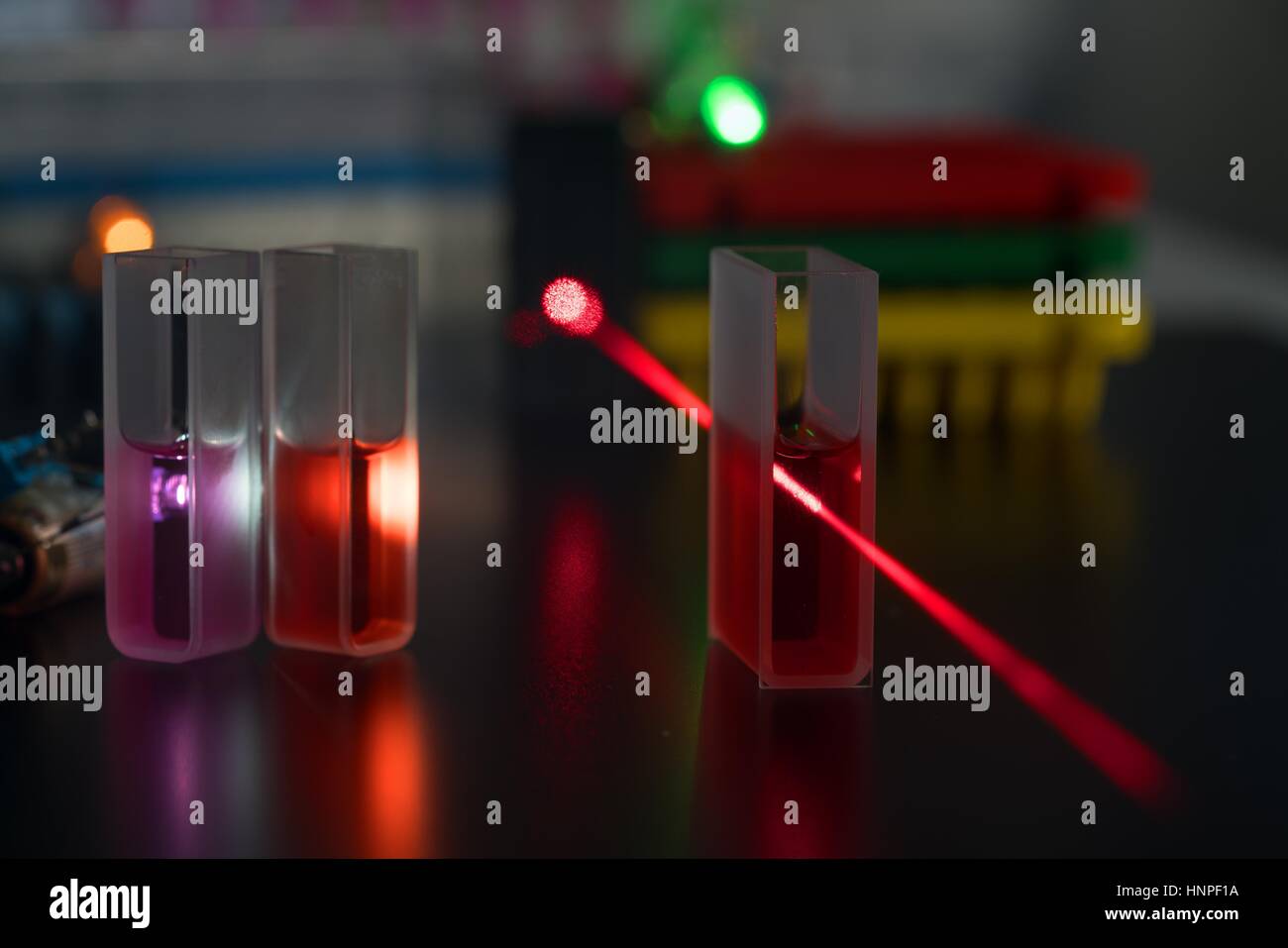 Quartz cuvette for laser chromatography with red liquid. Physical ...