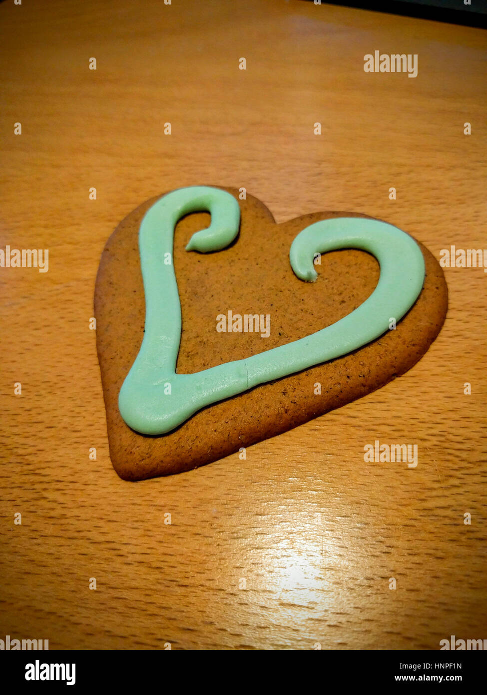A gingerbread biscuit in the shape of a heart decorated with green ...