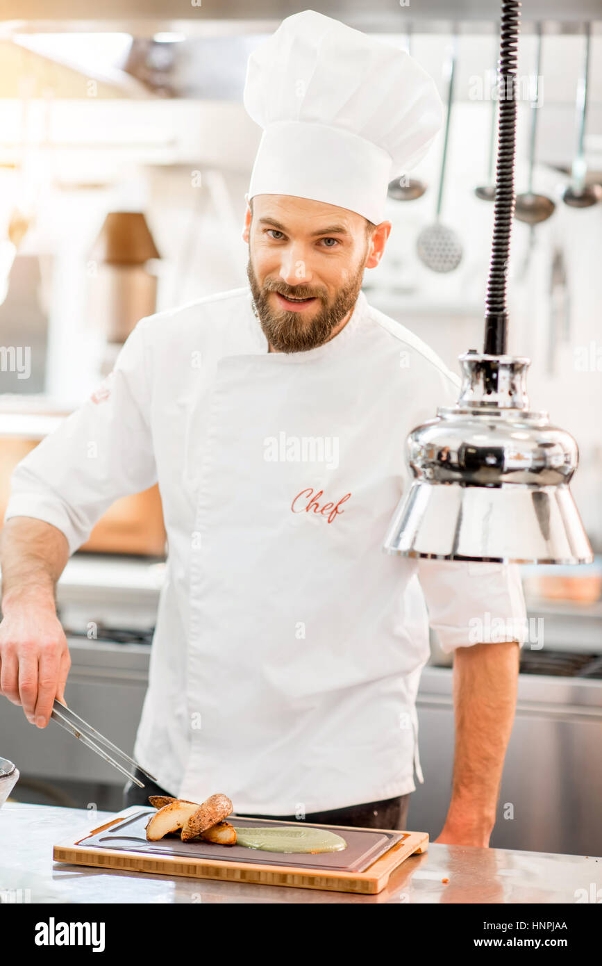 Chef cook in uniform finishing delicious meal at the restaurant kitchen ...