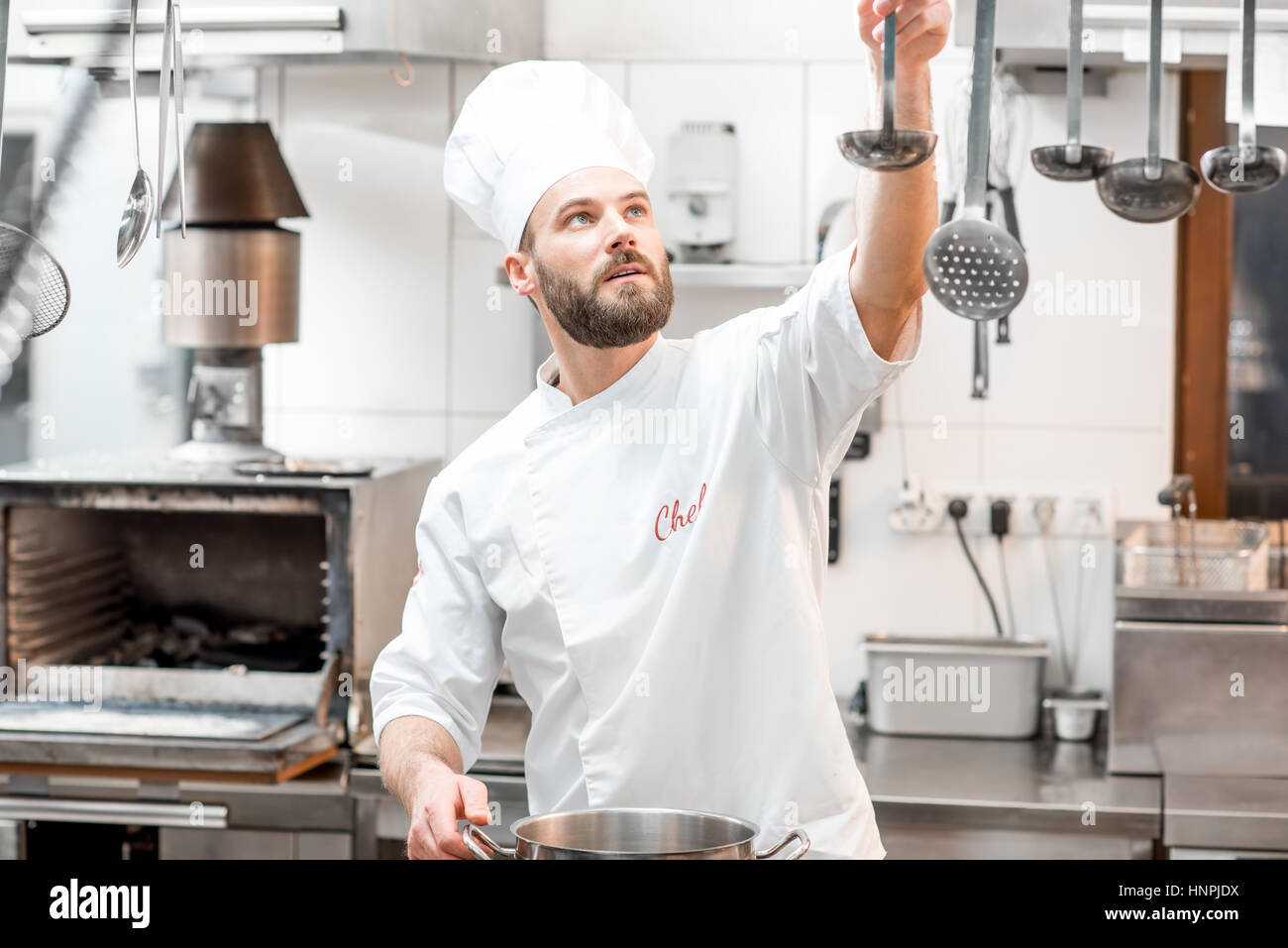 Handsome chef cook cooking food with pan and scoop at the restaurant ...