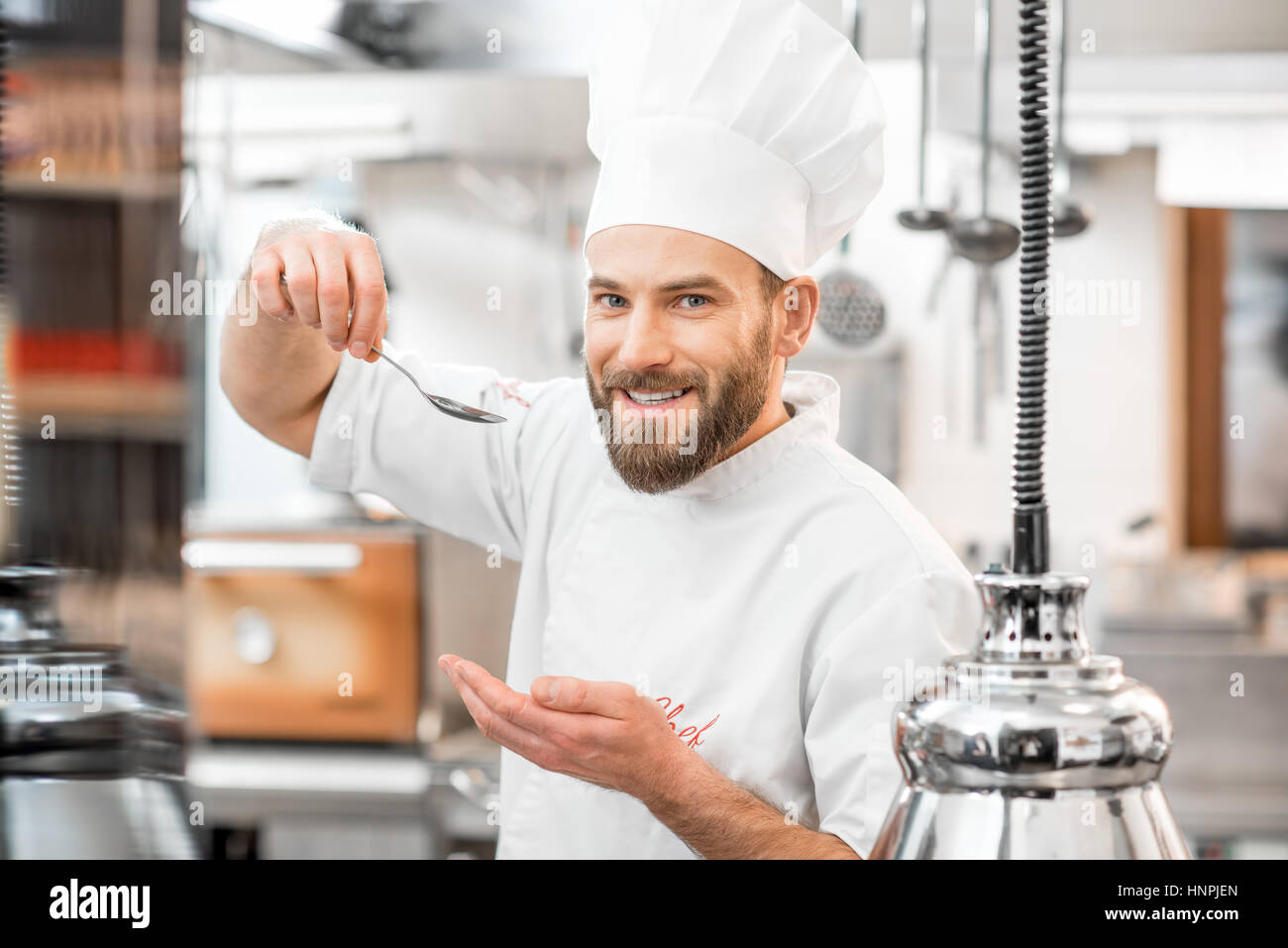Handsome chef cook tasting with spoon food at the beautiful restaurant ...