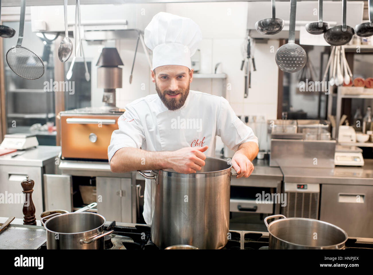 Portrait of a chef cook in uniform with big cooker at the restaurant ...