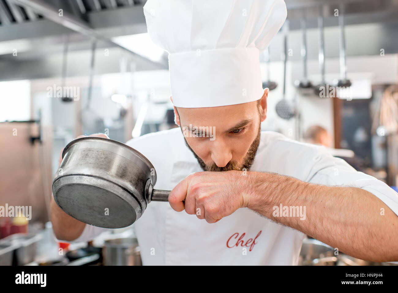 Handsome chef cook in uniform tasting sause at the kitchen Stock Photo ...